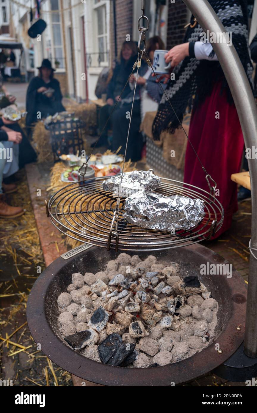 Potato in alumnium foil baked on charcoal barbecue grill outdoor in ...