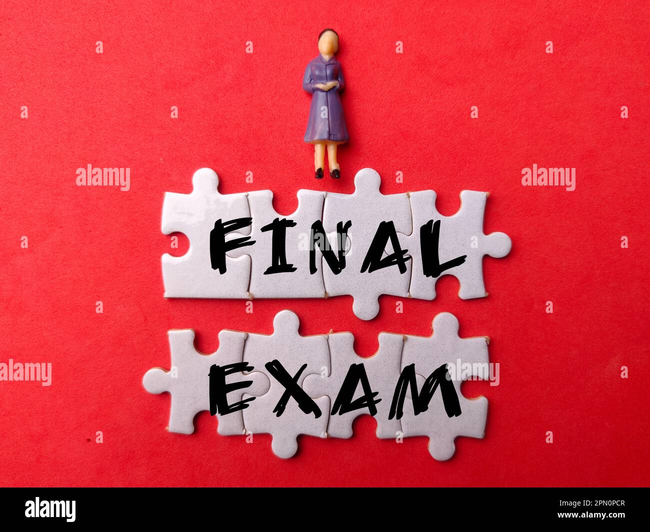 Miniature people and white puzzle FINAL EXAM on red background Stock ...