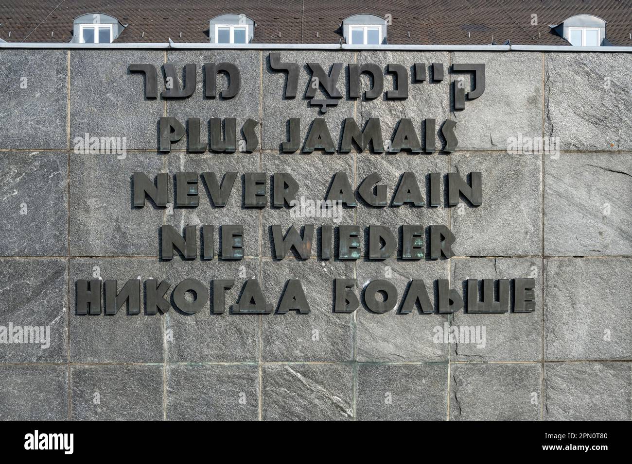 letters on a wall that read "never again" in Hebrew, French, English ...