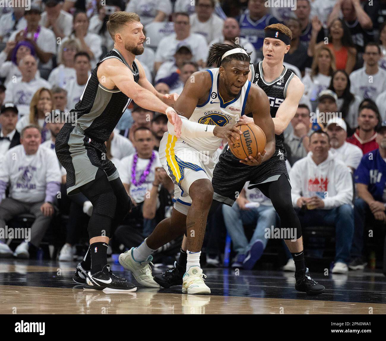Golden State Warriors forward Kevon Looney, center, grabs the ball between Sacramento Kings ...