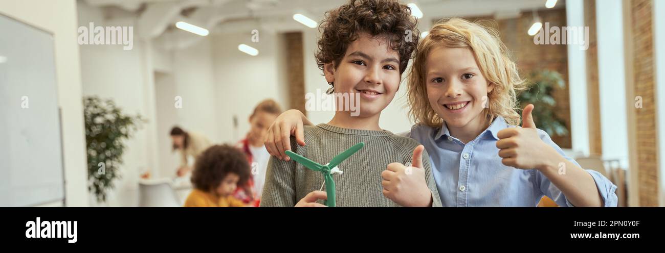 Our invention. Portrait of two happy boys showing thumbs up while ...