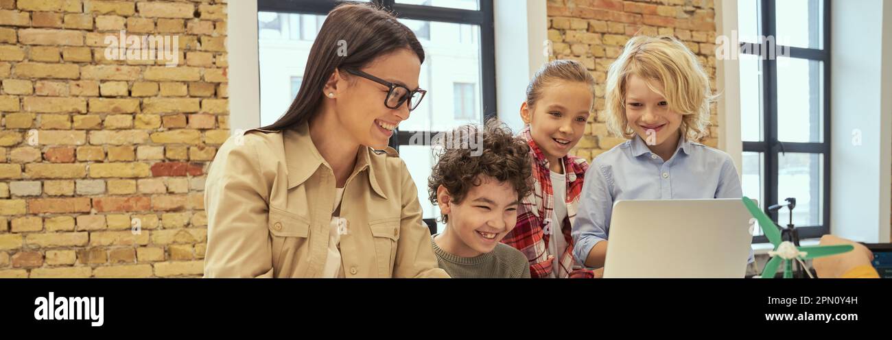 Clever kids learn how to assemble robot using laptop, sitting at the ...