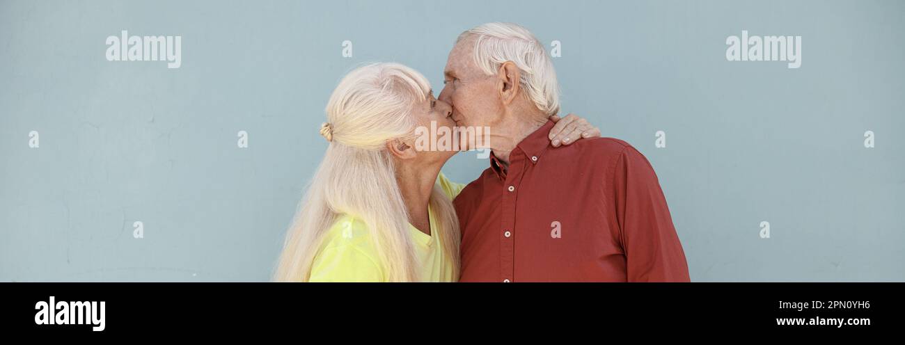 Adorable Senior Pair Of Sweethearts Kisses On Light Grey Background