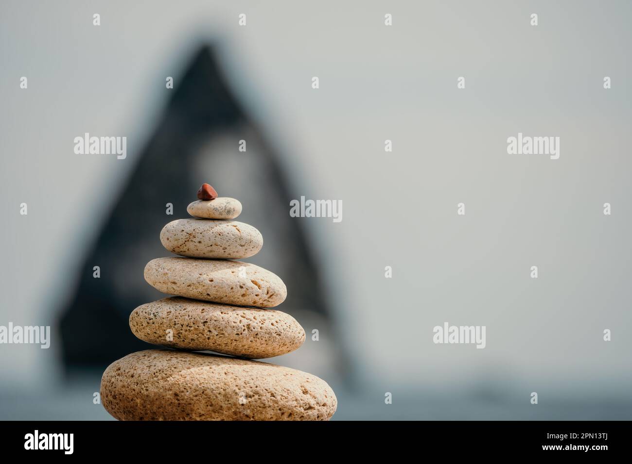 Pyramid stones on the seashore with warm sunset on the sea background. Happy holidays. Pebble ...