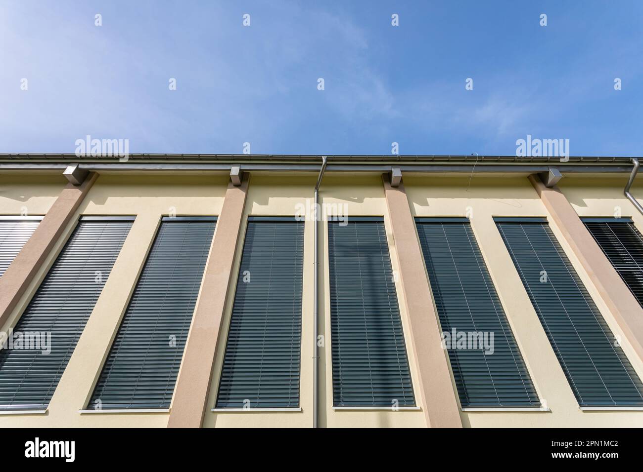 The facade of the sports hall with large windows covered with blinds ...