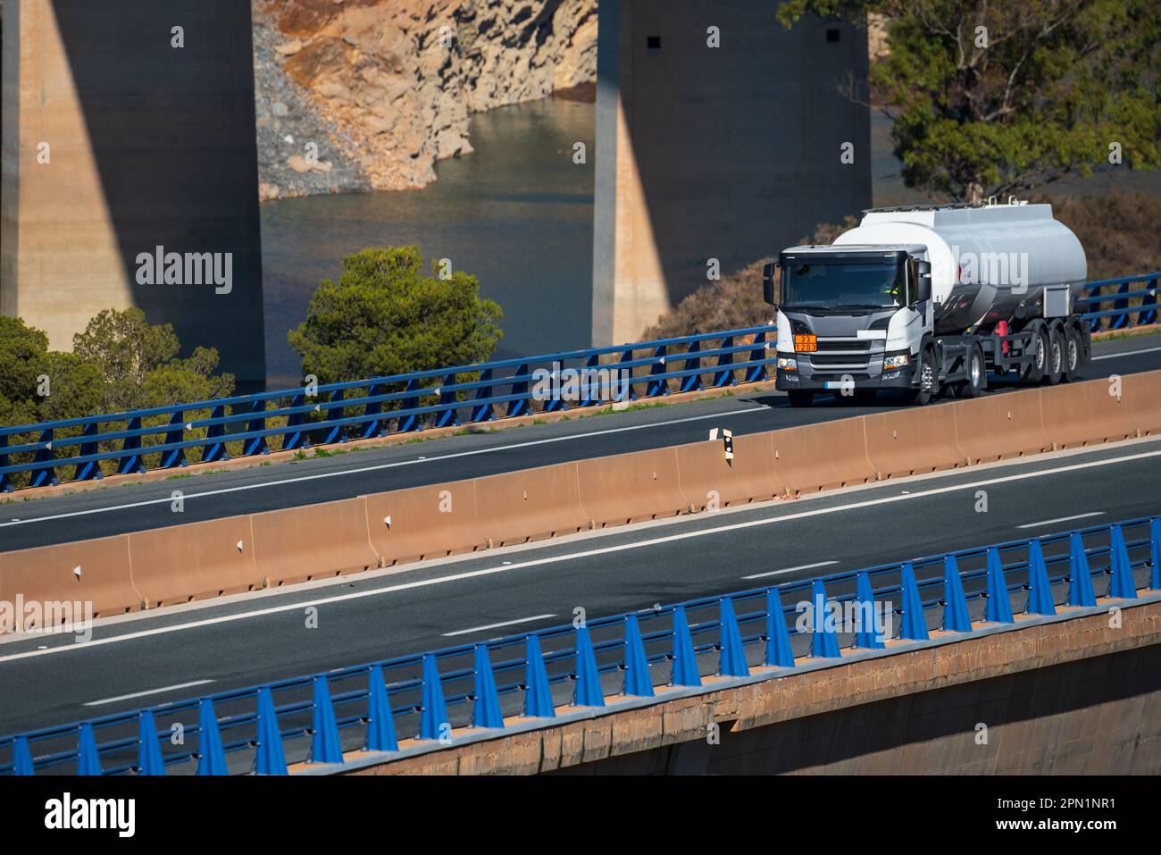 Fuel tanker truck driving on the highway with the pillars of a bridge ...