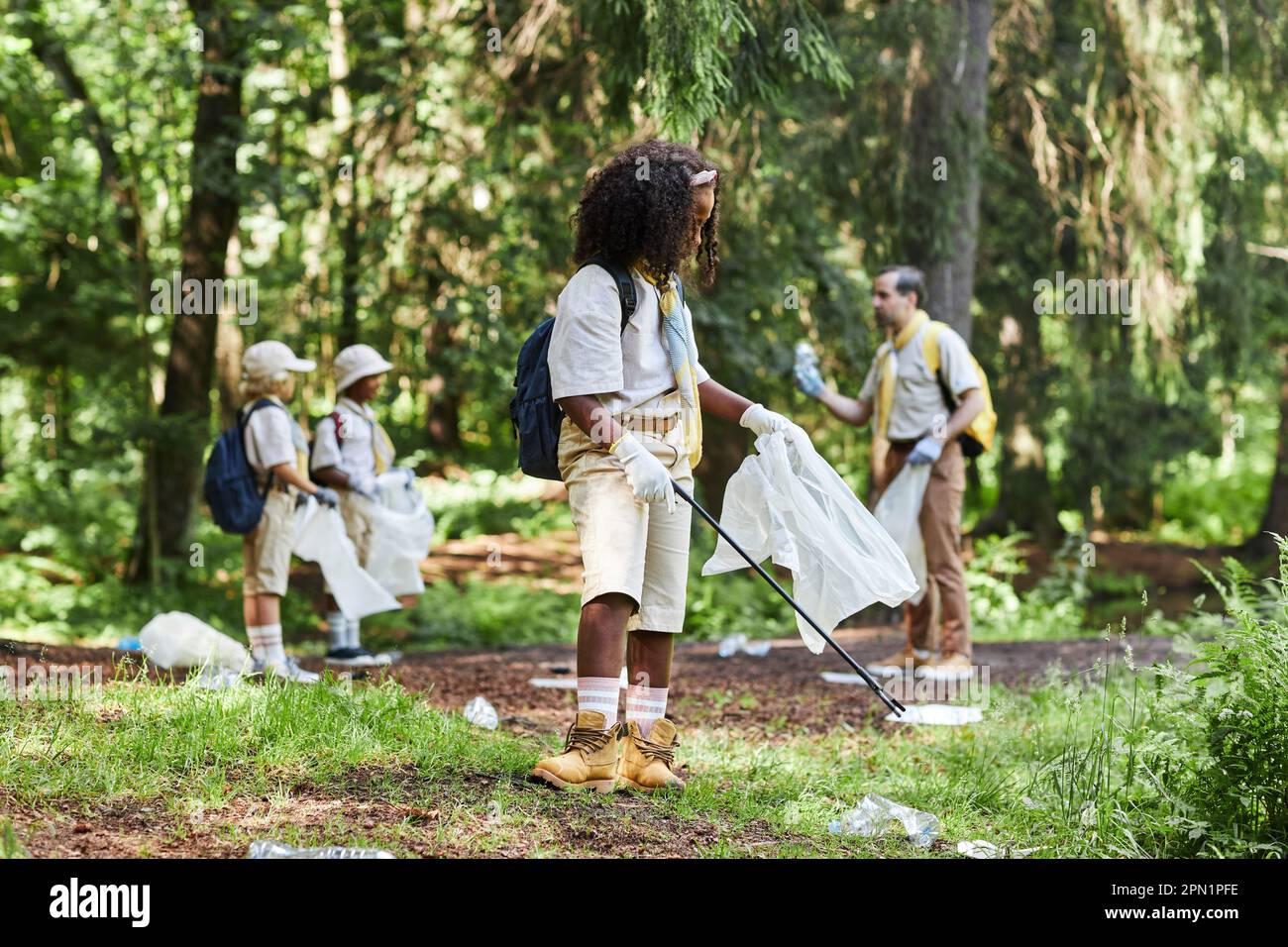 Diverse group of children scouts helping clean forest and holding trash ...