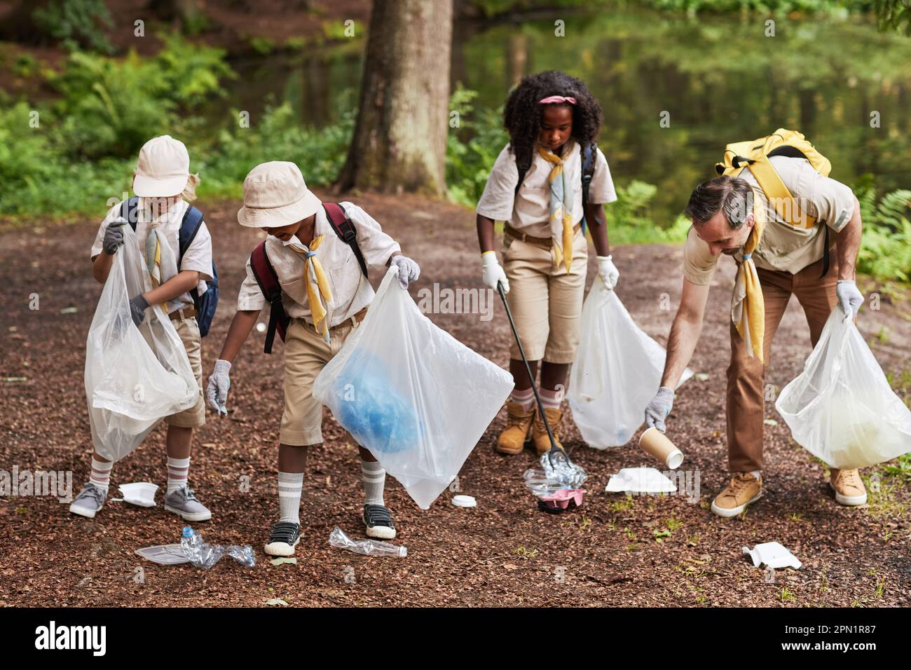 Full length diverse group of scouts picking up trash in forest during ...