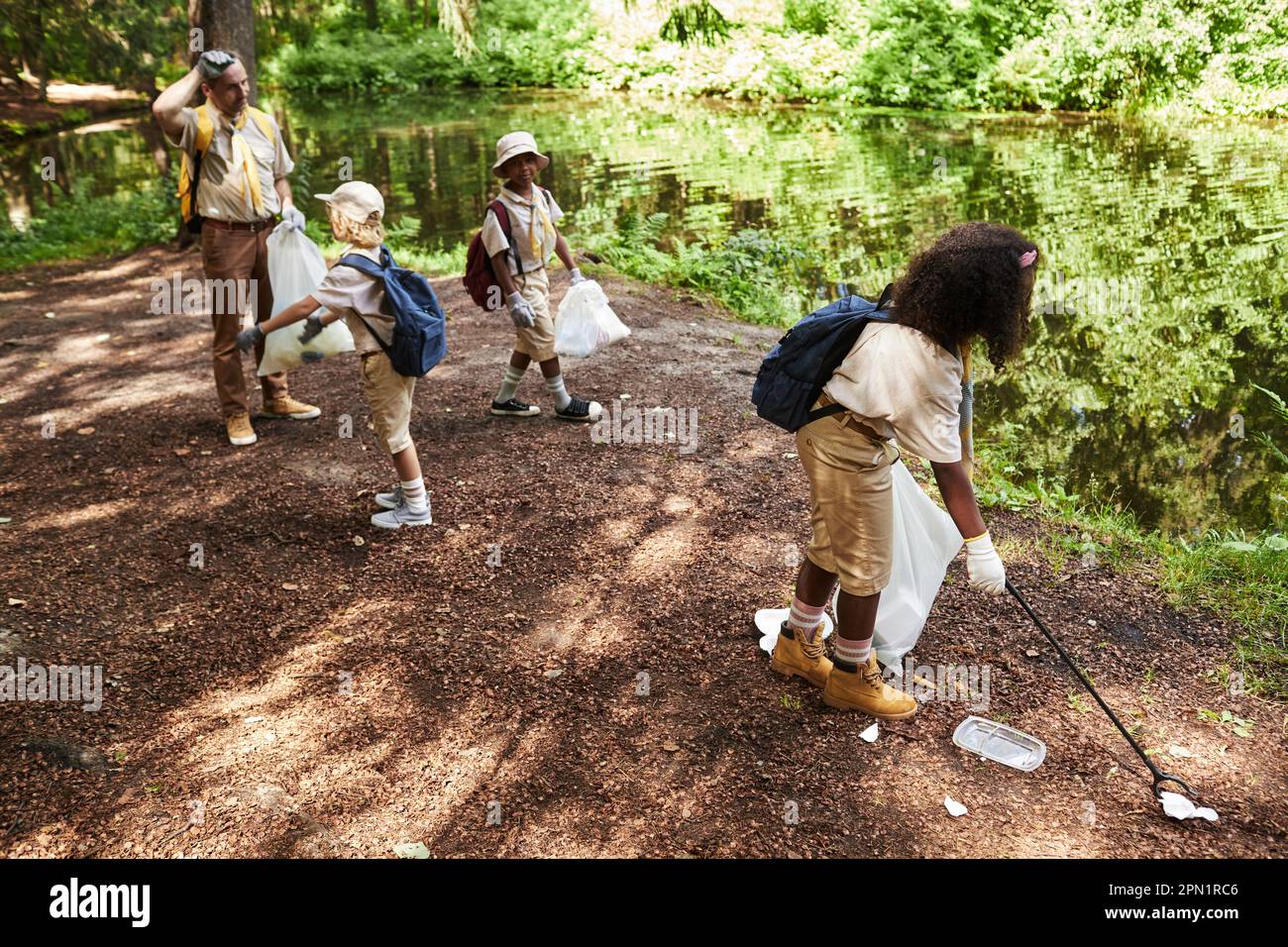 High angle view at diverse group of scouts picking up trash in forest ...