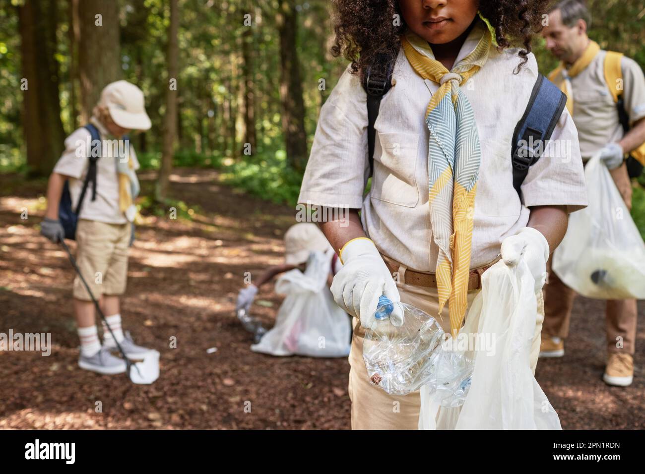 Close Up Of Girl Scout Picking Up Trash In Park During Eco Awareness Field Trip Copy Space