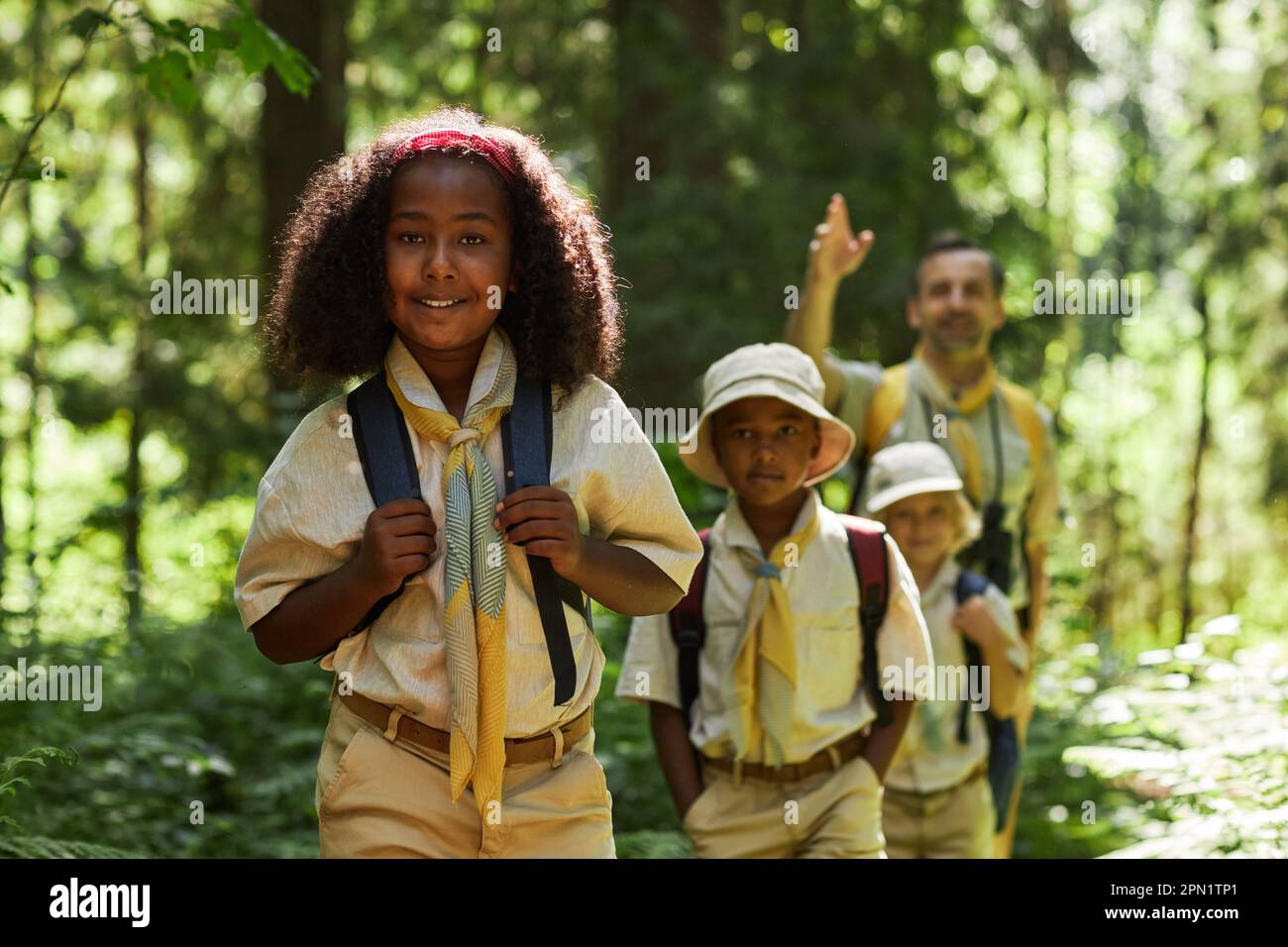 Waist up portrait of black girl with group of scouts hiking in forest ...