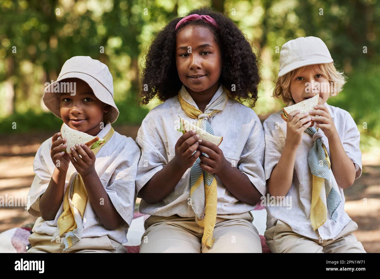 Front view at group of scouts enjoying lunch break during hiking trip ...