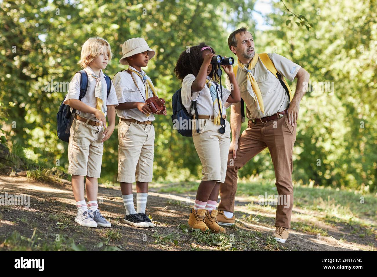 Side view at diverse group of scouts in forest exploring nature with ...