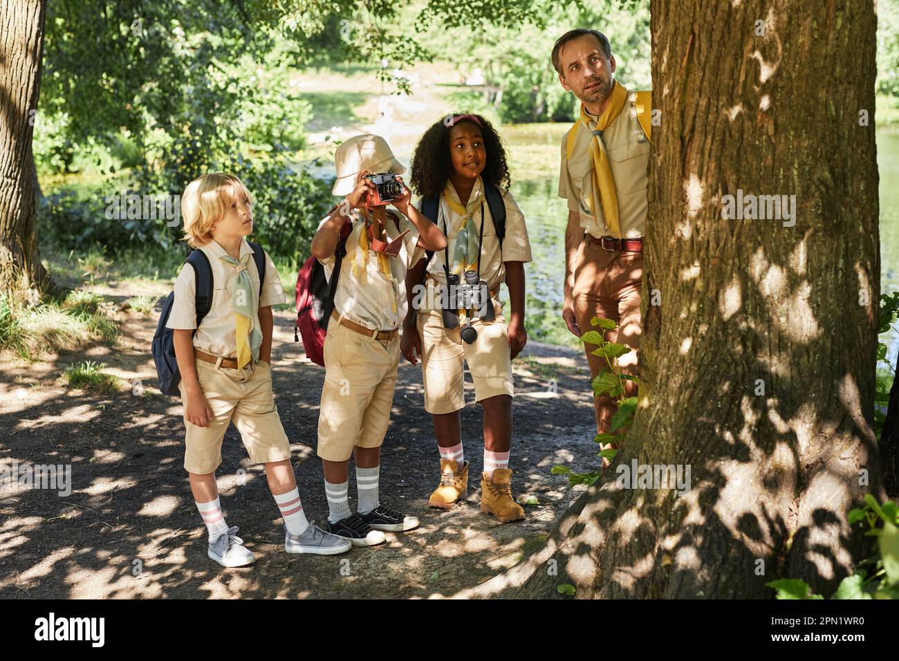 Diverse group of little scouts in forest exploring nature and looking ...