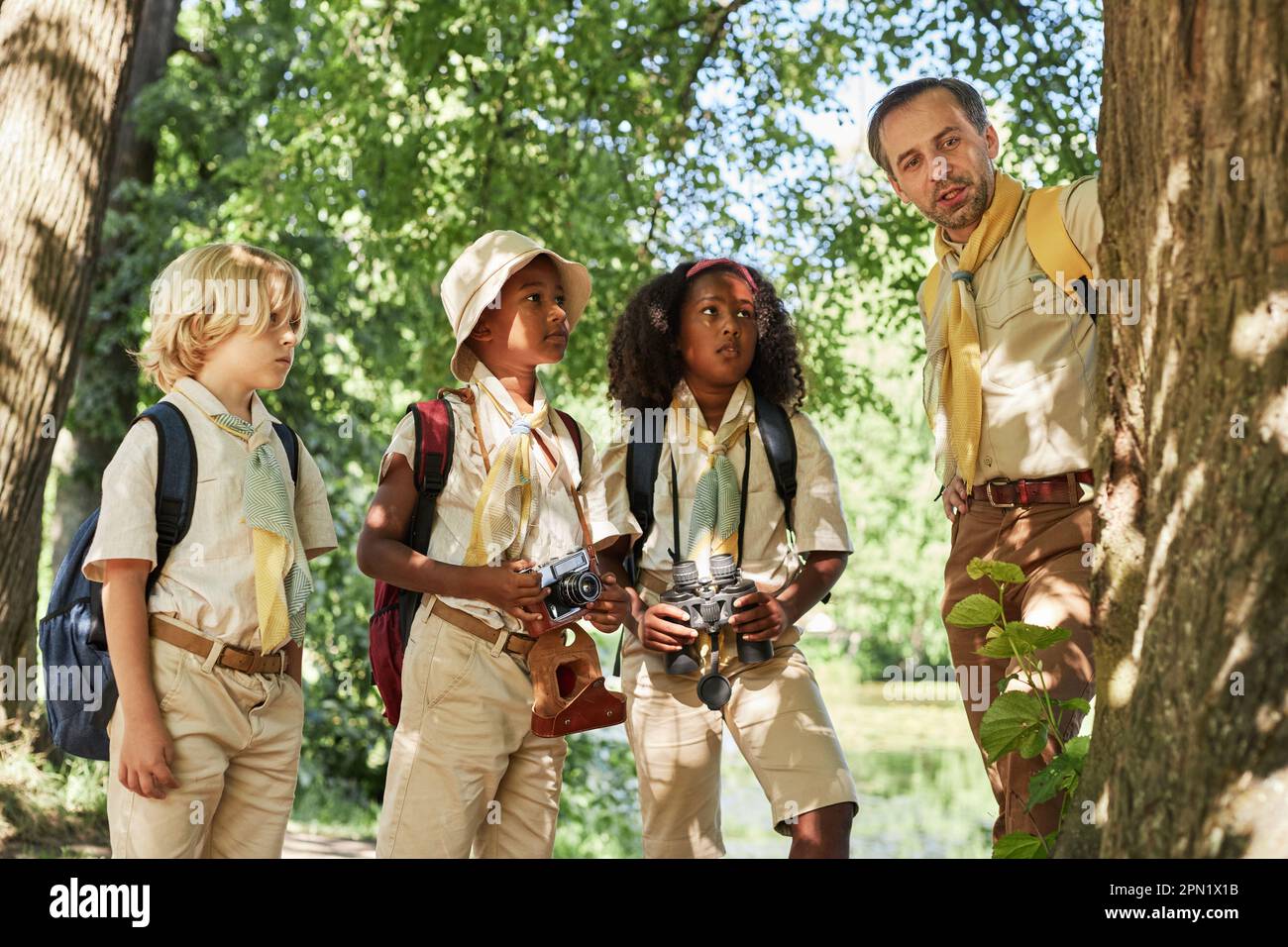Waist up portrait of little scouts exploring forest with adult leader ...