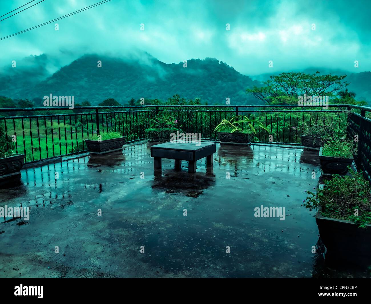 A wooden outdoor patio table with an umbrella in the middle of a rain ...