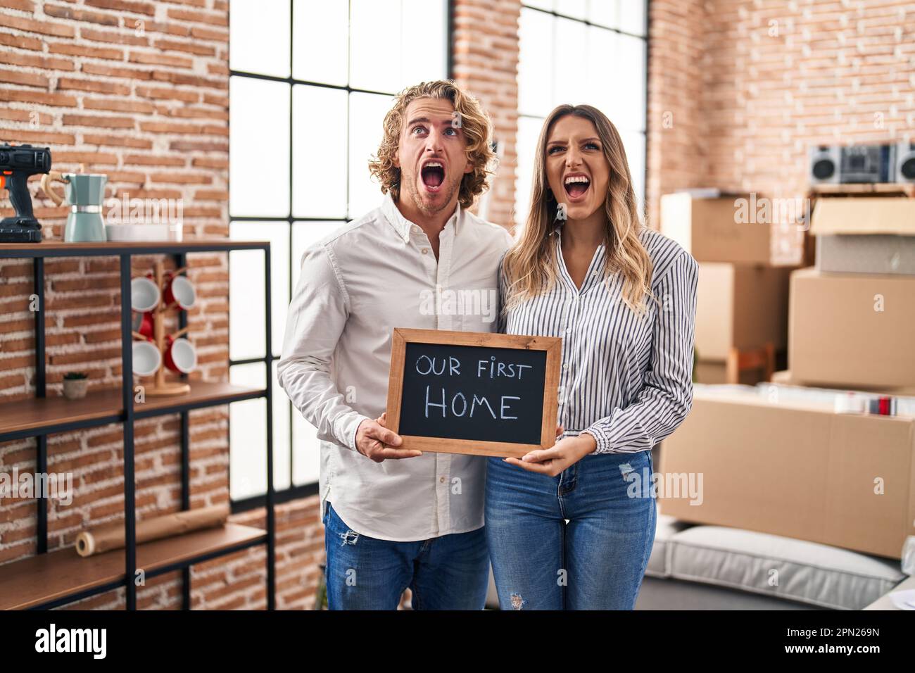 Young couple moving to a new home angry and mad screaming frustrated ...