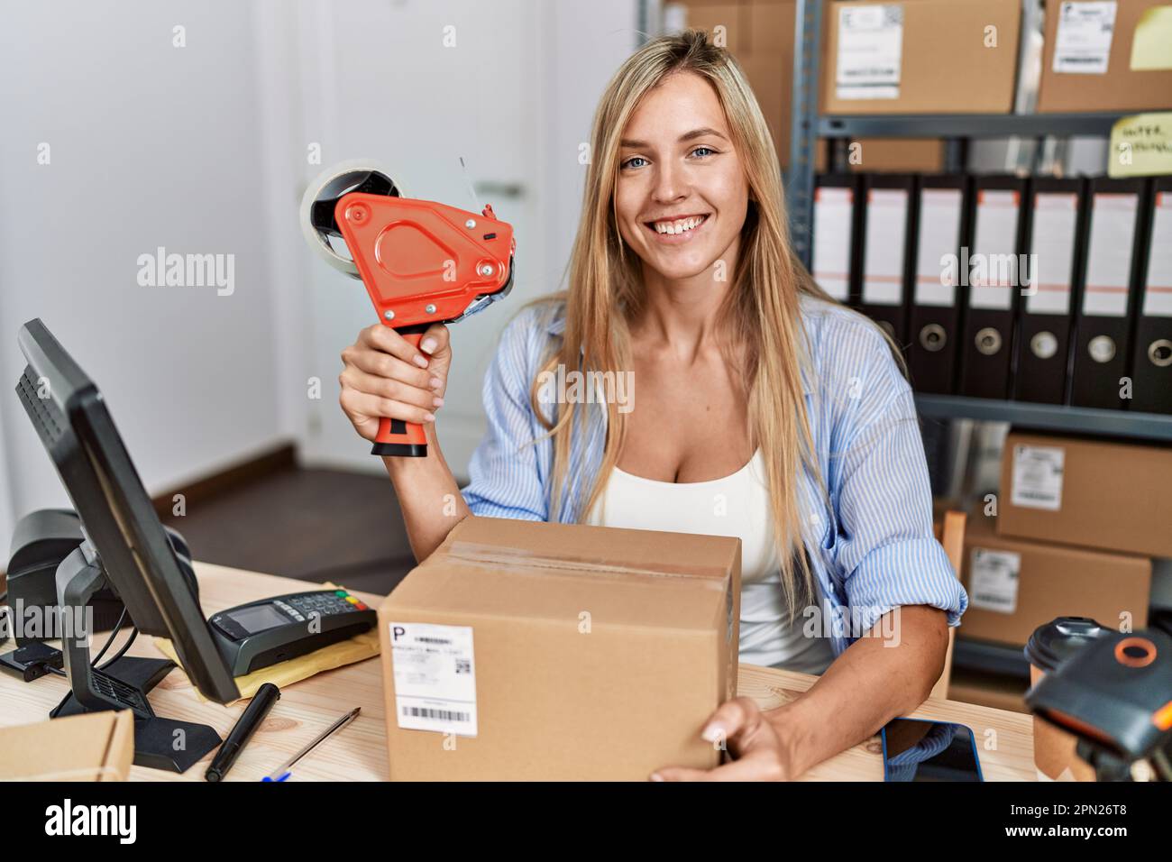 Young blonde woman ecommerce business worker holding packing tape ...