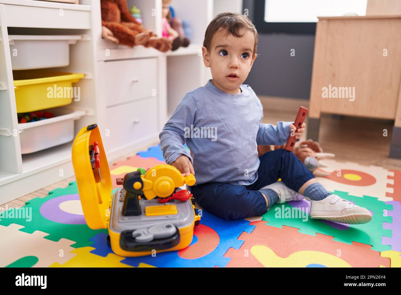 Adorable hispanic boy playing with tools toy sitting on floor at ...
