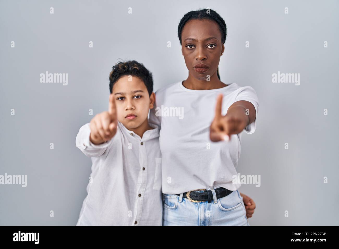 Young mother and son standing together over white background pointing ...