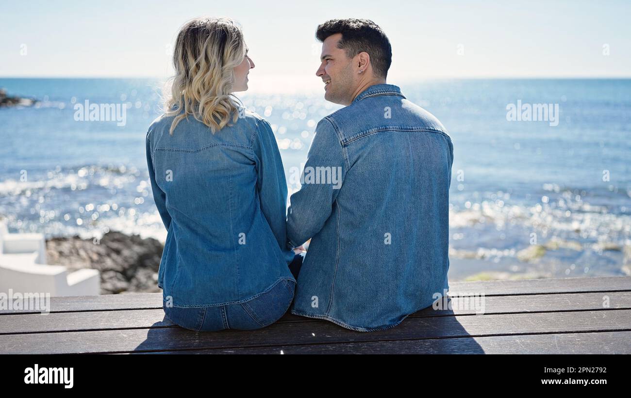 Man and woman couple sitting on bench backwards at seaside Stock Photo ...