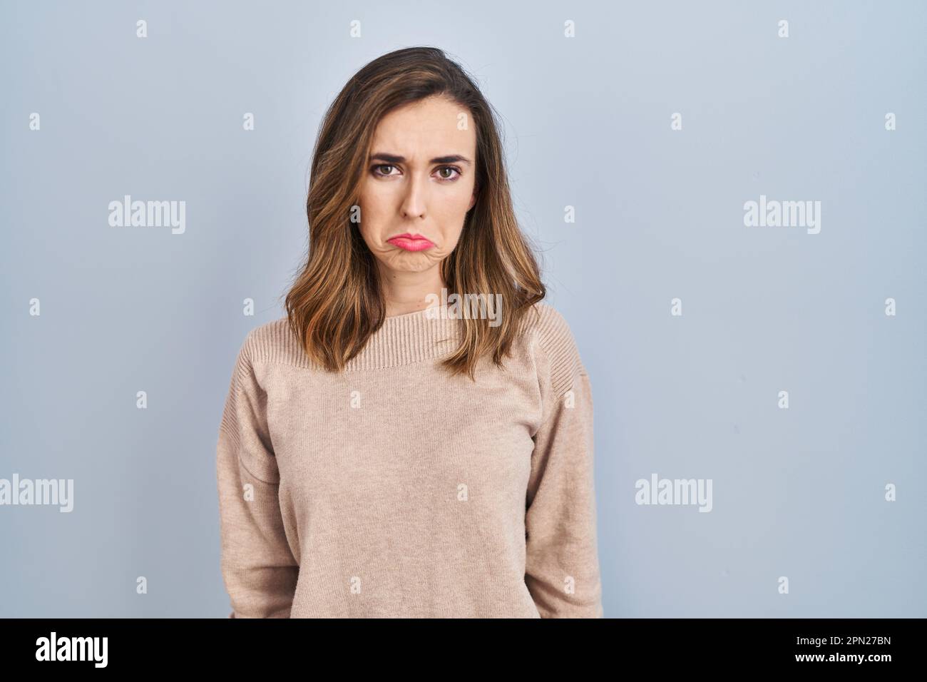 Young woman standing over isolated background depressed and worry for ...