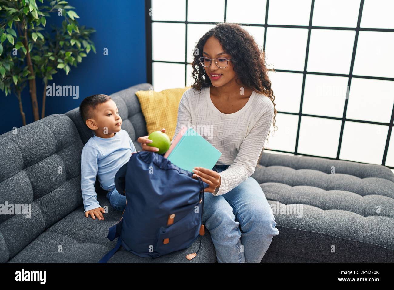 Mother and son prepare school backpack sitting on sofa at home Stock ...
