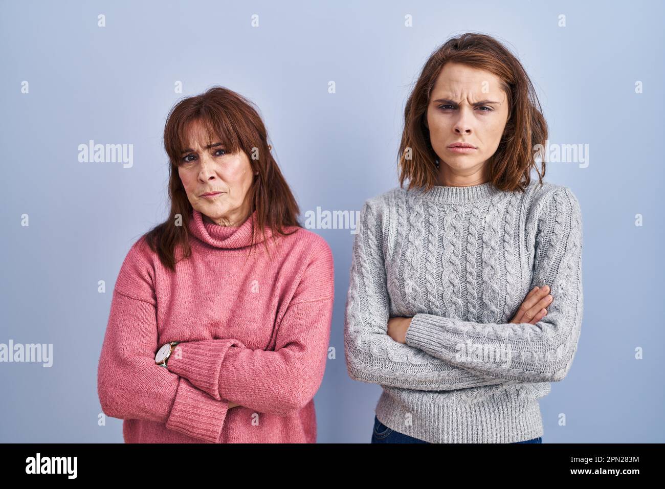 Mother And Daughter Standing Over Blue Background Skeptic And Nervous