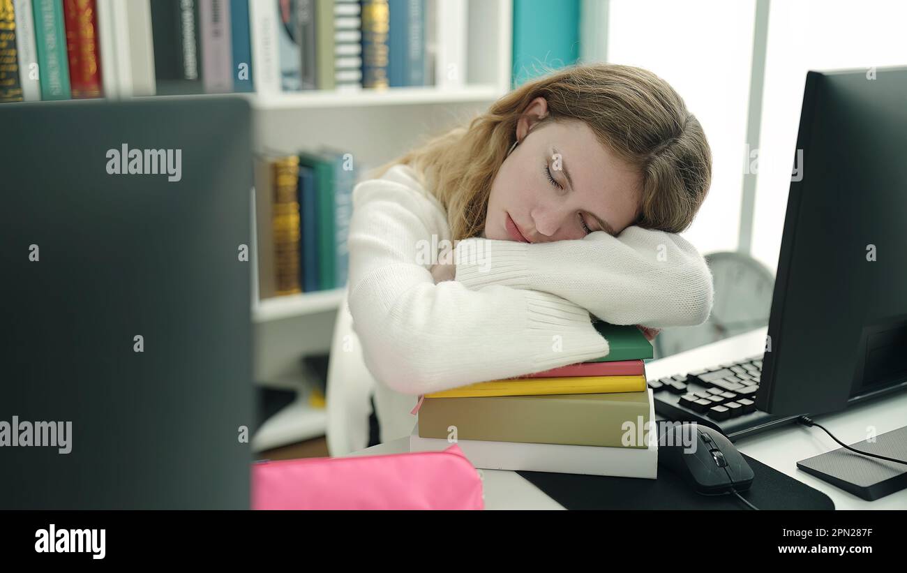Young blonde woman student leaning on books sleeping at library ...