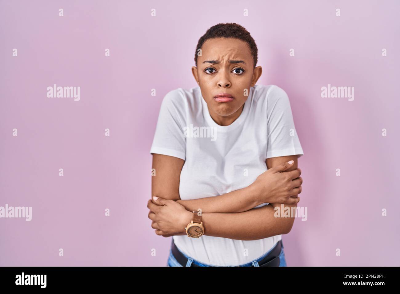 Beautiful african american woman standing over pink background shaking ...