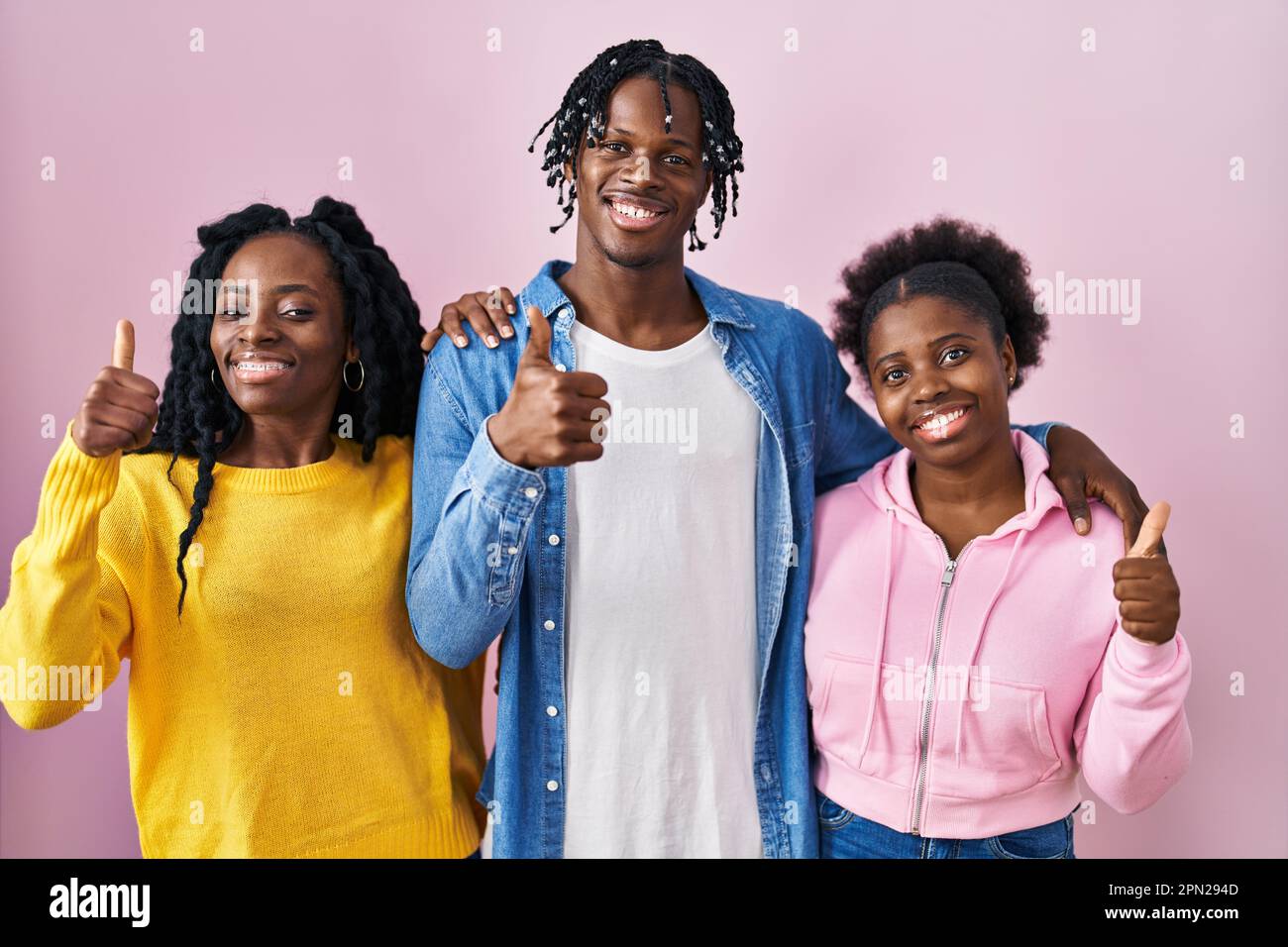 Group of three young black people standing together over pink ...