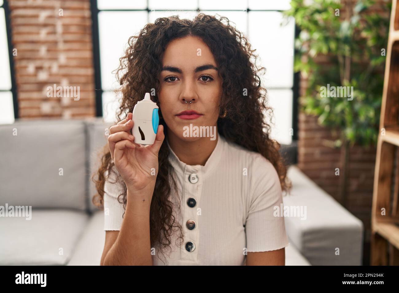 Young hispanic woman using glucose meter thinking attitude and sober ...