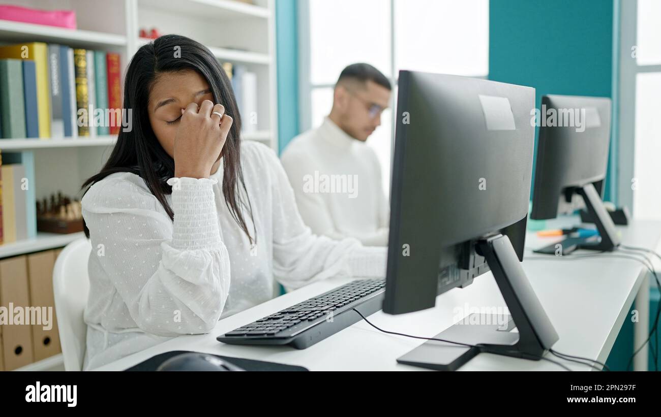 Man and woman students using computer stressed at university classroom ...
