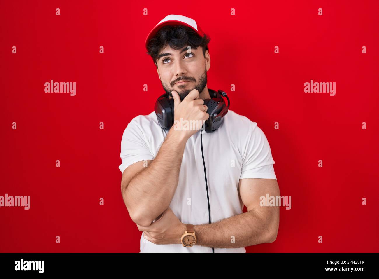 Hispanic man with beard wearing gamer hat and headphones looking ...