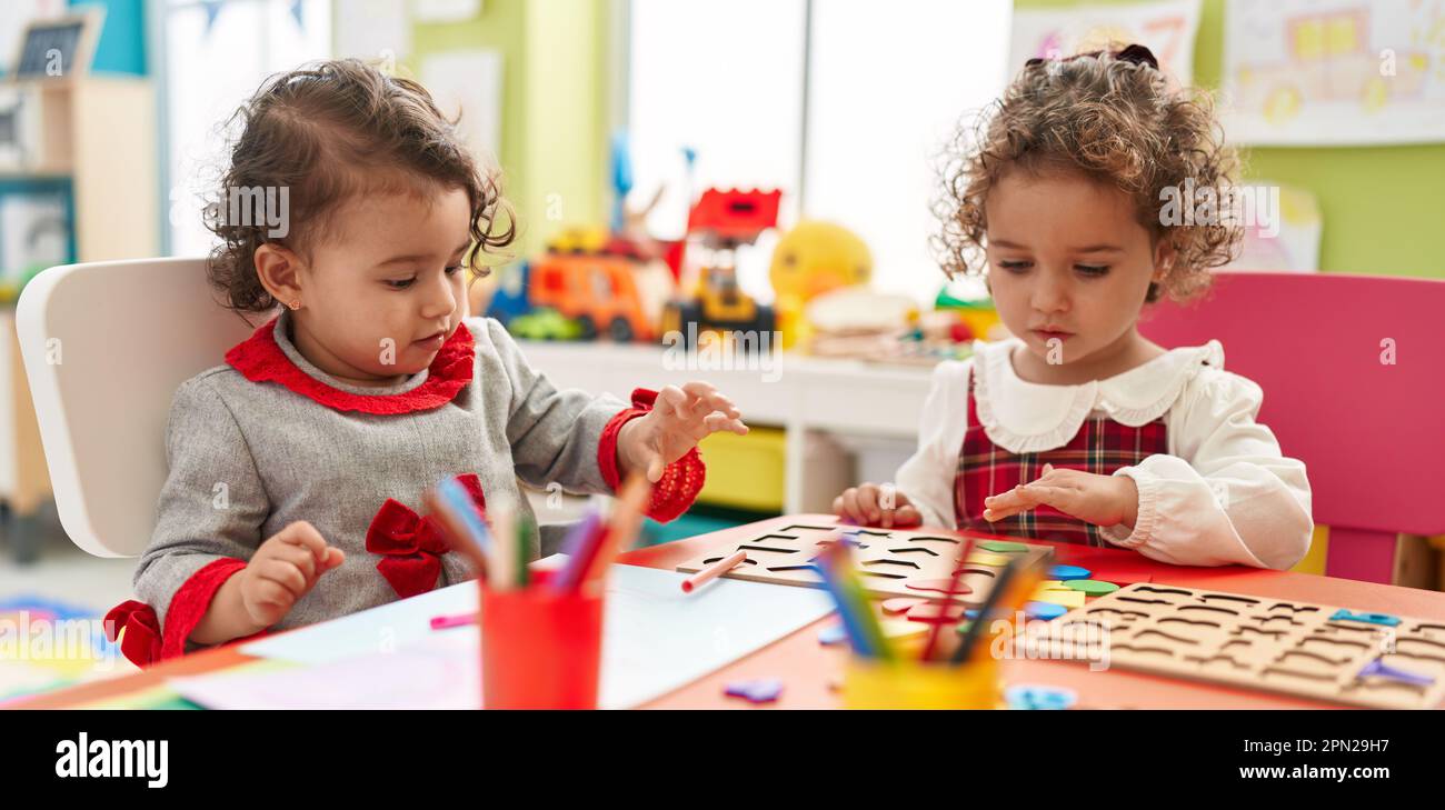Adorable girls playing with maths puzzle game sitting on table at ...
