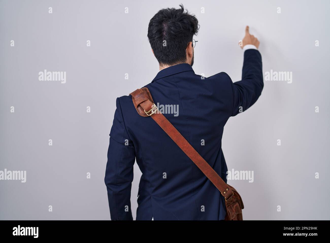 Hispanic man with beard wearing business clothes posing backwards ...