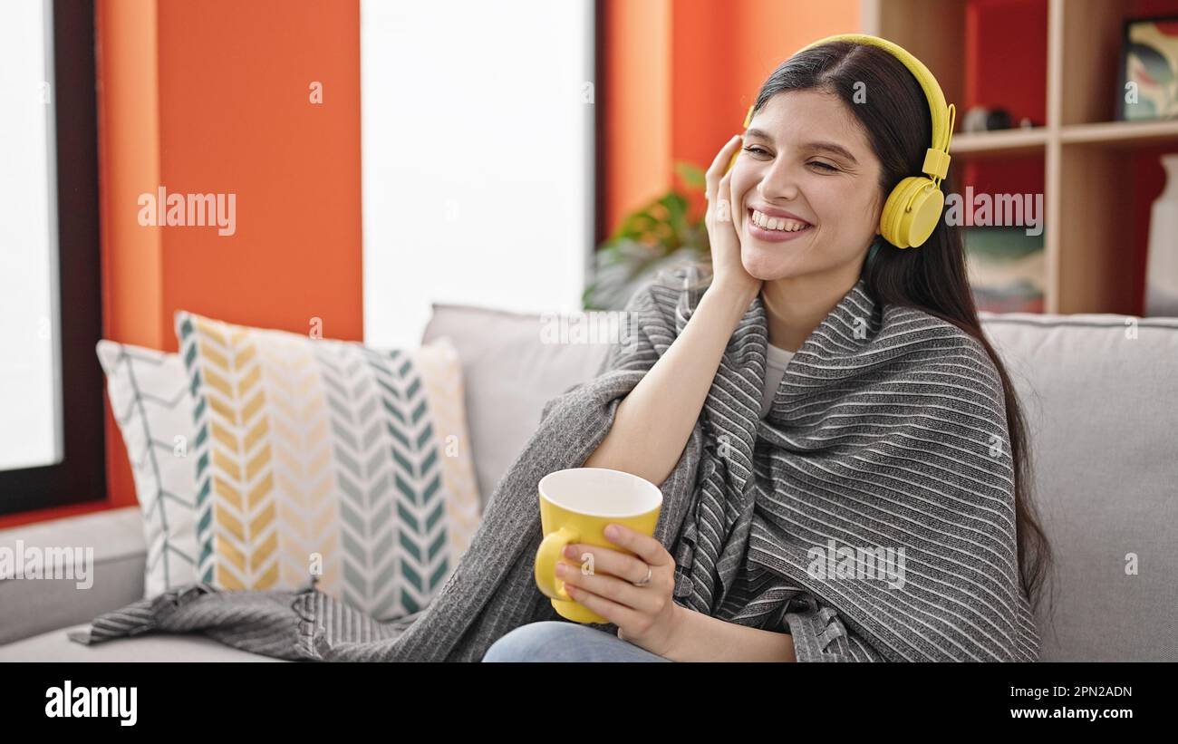 Young beautiful hispanic woman listening to music drinking coffee at ...