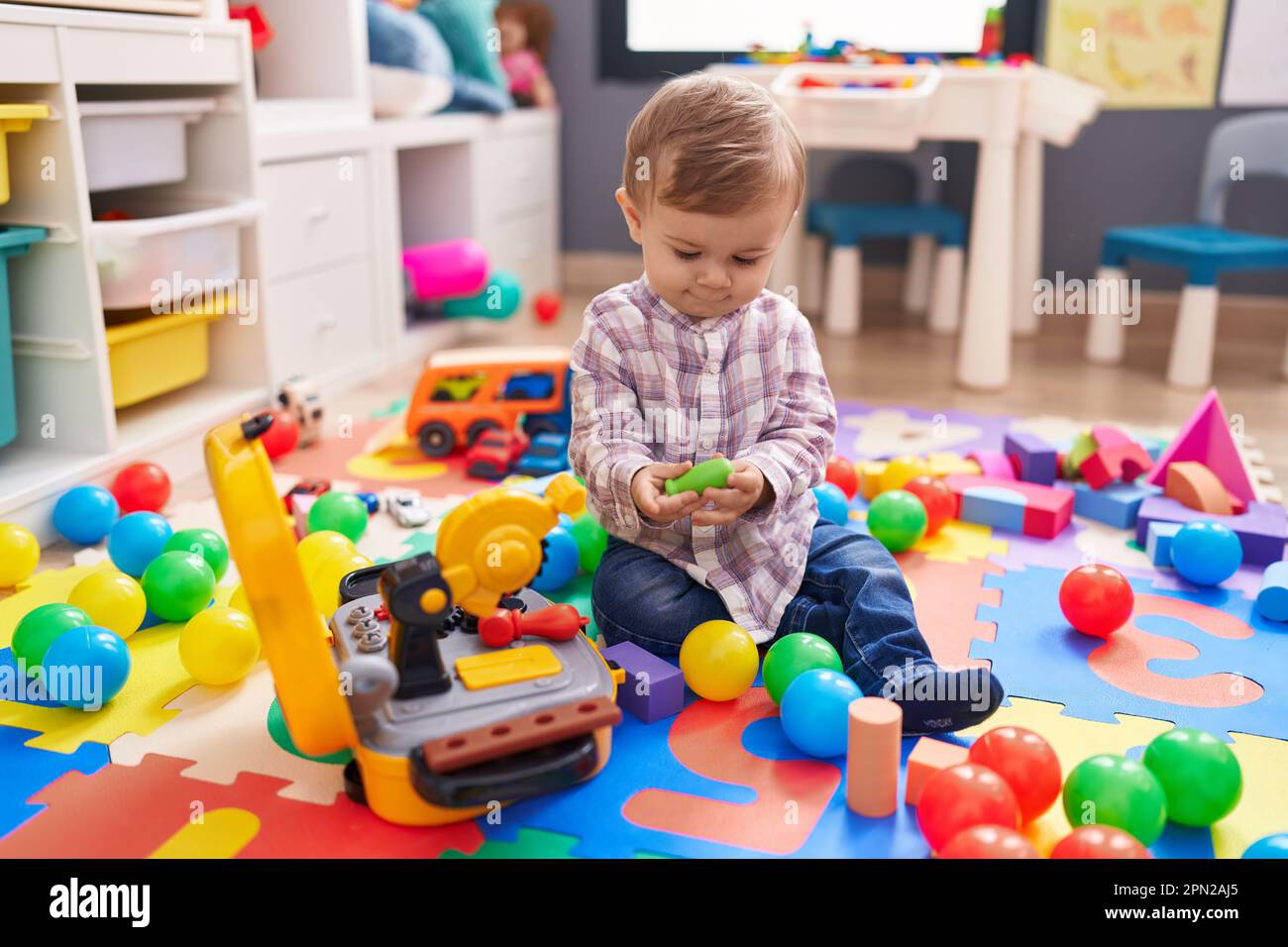Adorable caucasian boy playing with balls sitting on floor at ...