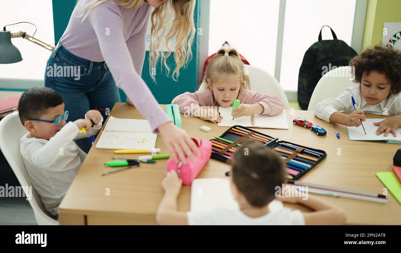 Woman and group of kids having lesson sitting on table at classroom ...