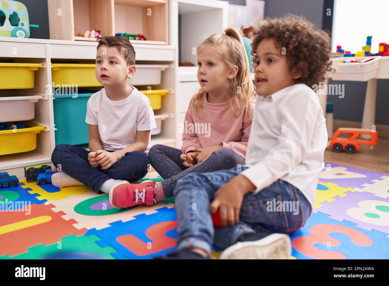 Group of kids sitting on floor with relaxed expression at kindergarten ...
