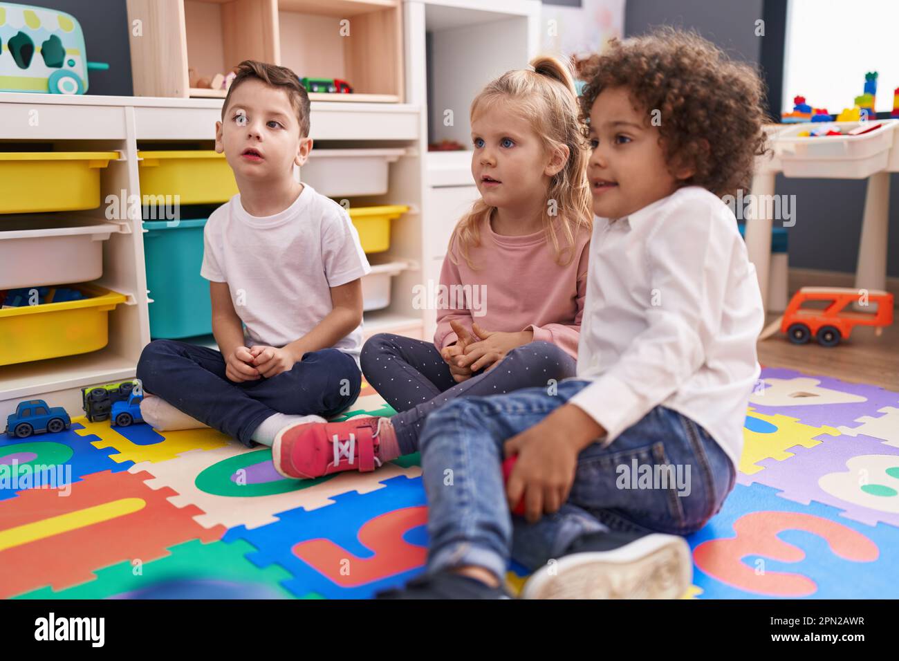 Group of kids sitting on floor with relaxed expression at kindergarten ...