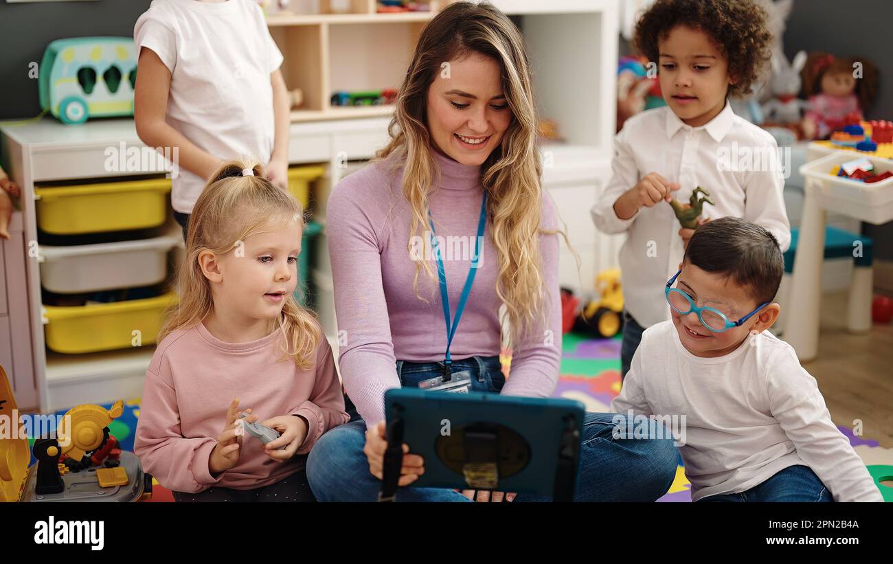 Woman and group of kids having lesson using touchpad at kindergarten ...