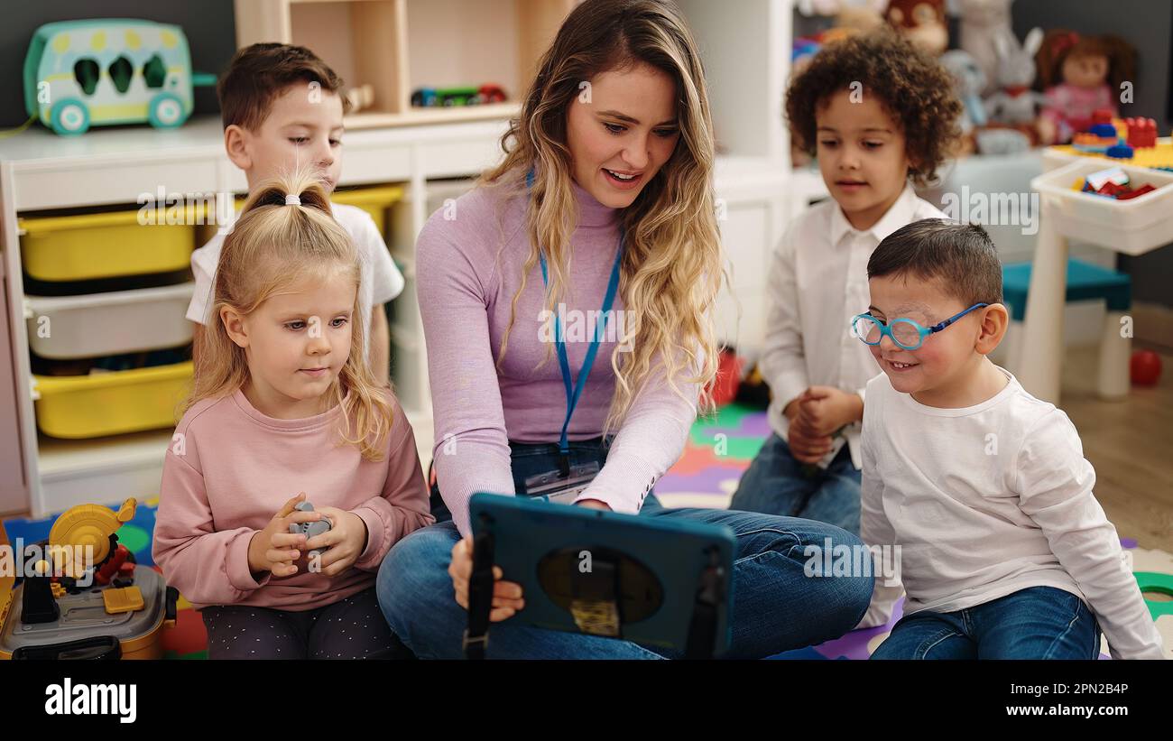 Woman and group of kids having lesson using touchpad at kindergarten ...