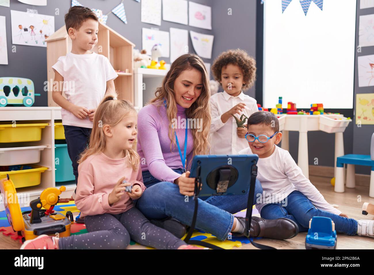 Woman and group of kids having lesson using touchpad at kindergarten ...