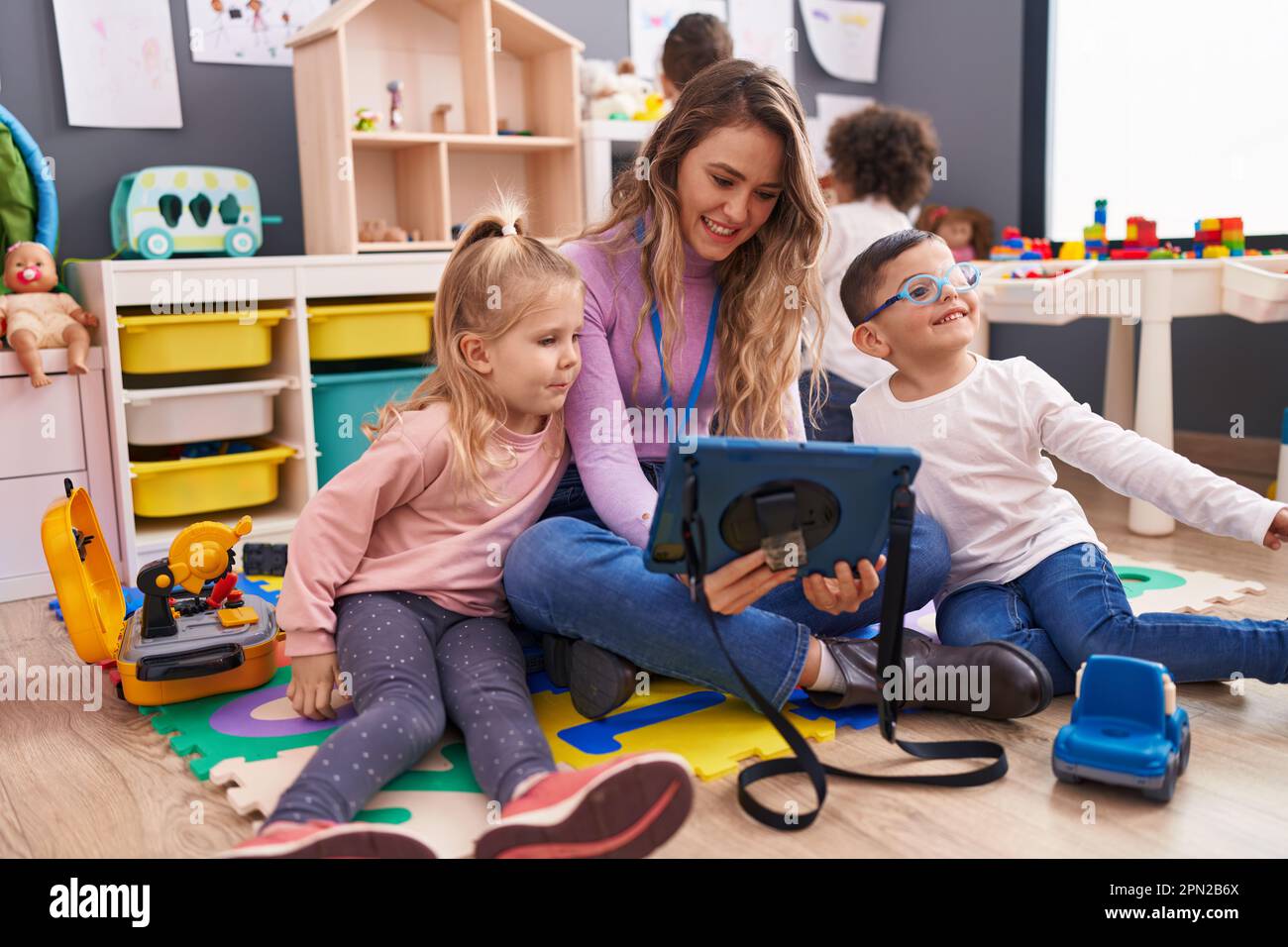 Woman and group of kids having lesson using touchpad at kindergarten ...