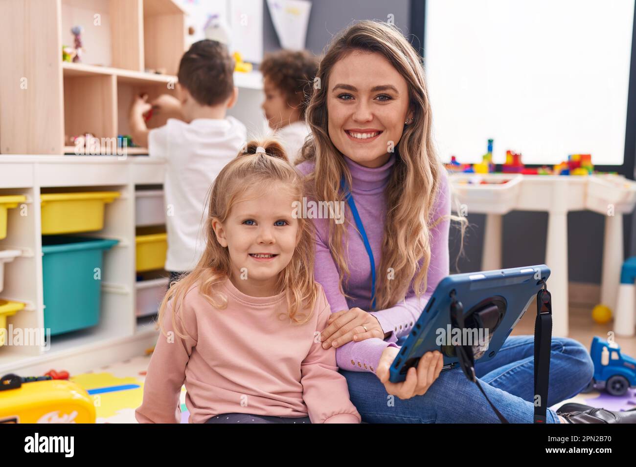 Woman and group of kids having lesson using touchpad at kindergarten ...