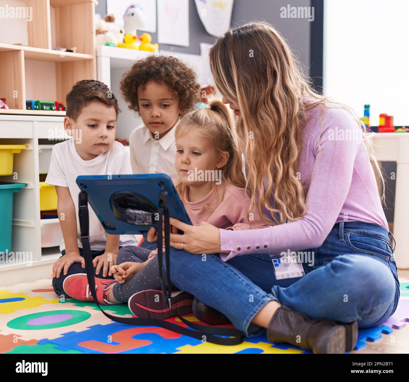 Woman and group of kids having lesson using touchpad at kindergarten ...