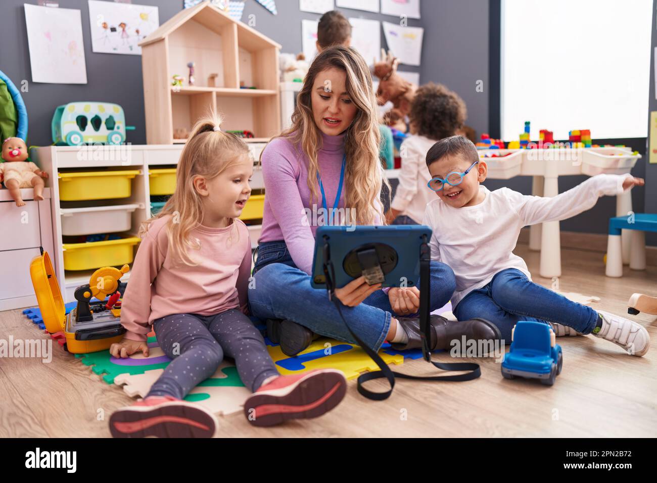 Woman and group of kids having lesson using touchpad at kindergarten ...