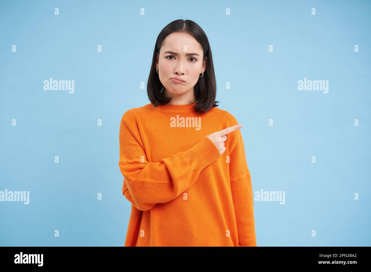Upset brunette girl 25 years old, points right at banner, copy space on ...