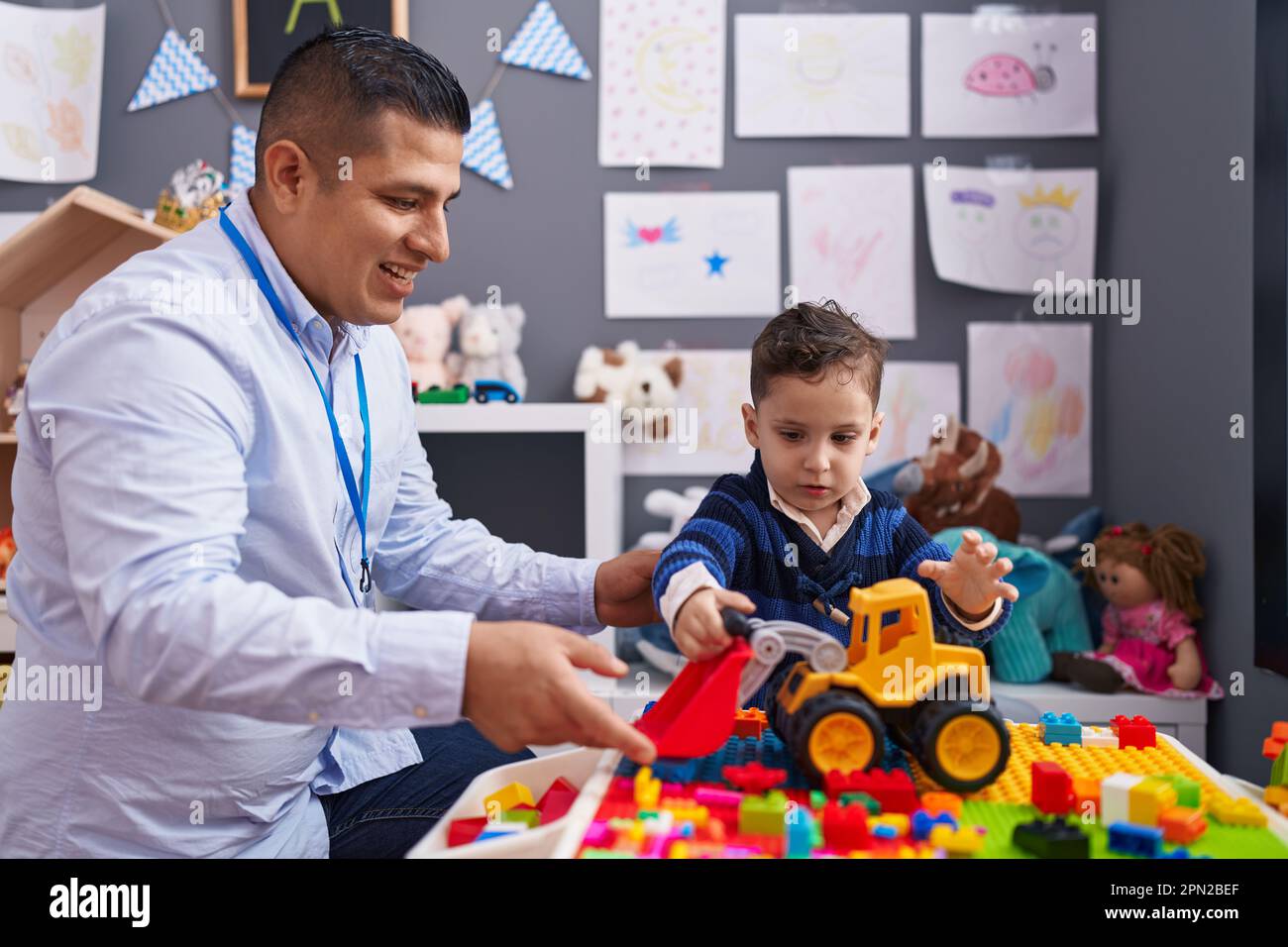 Hispanic man and boy playing with construction blocks and tractor toy ...